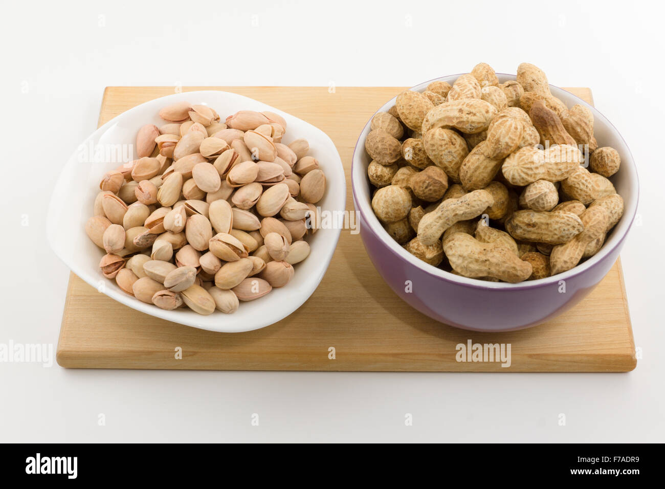 the platefuls of different nuts stand on a plate on a white background ...