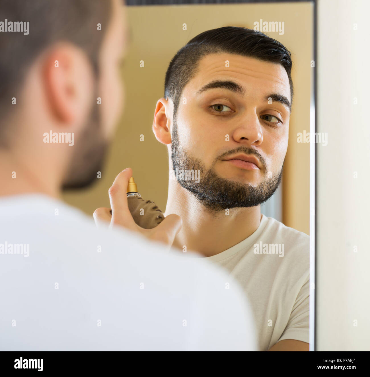 Attractive man spraying fragrance perfume at home Stock Photo - Alamy