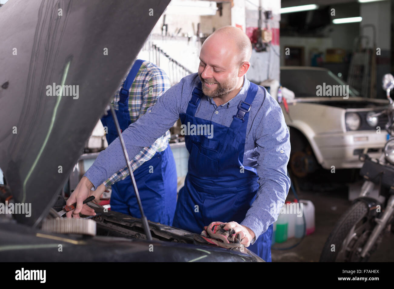 Professional positive mechanics repairing car of client Stock Photo - Alamy