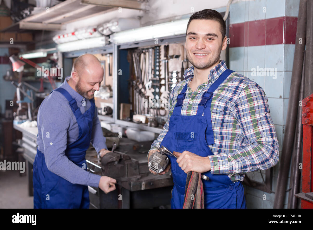 Two happy positive mechanics working in the workshop Stock Photo - Alamy