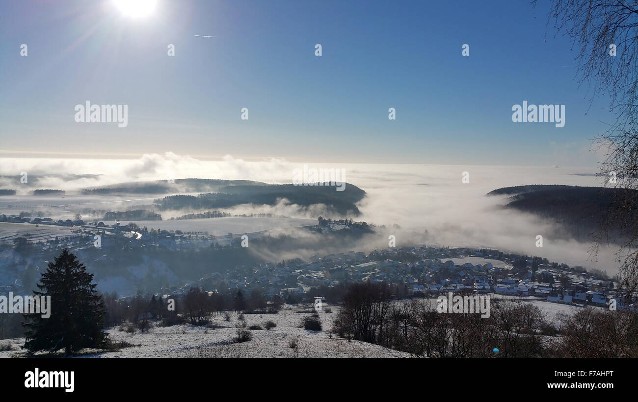 A valley shrouded in fog surrounding the small town Rauenstein, Germany ...
