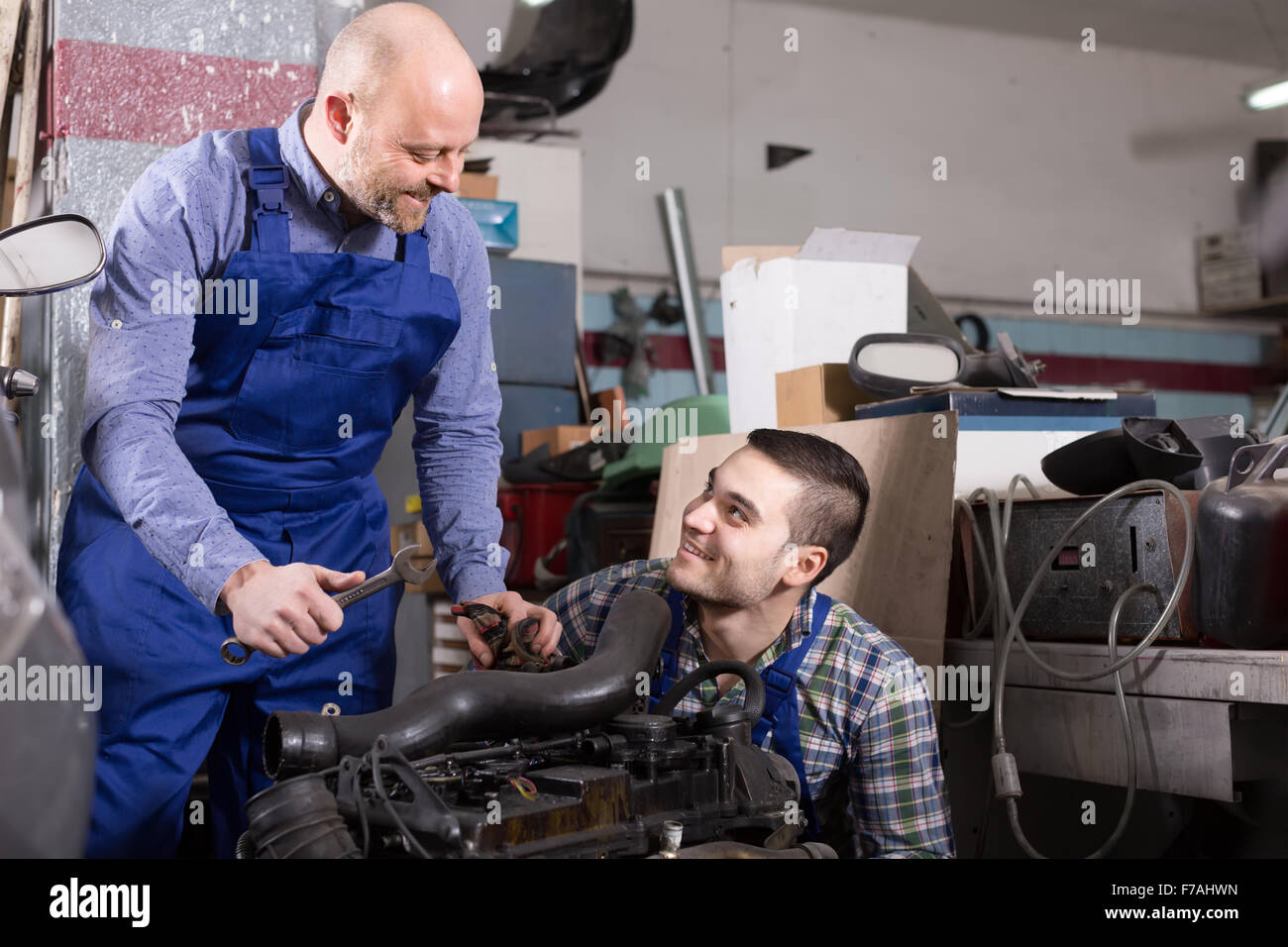 Portrait of two smiling professional car mechanics working together at ...