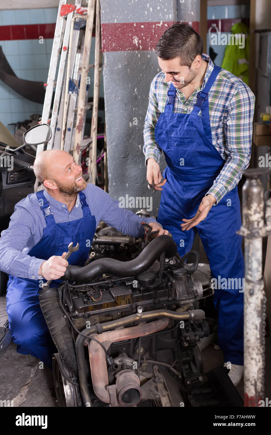 Portrait of two happy professional car mechanics working together at ...