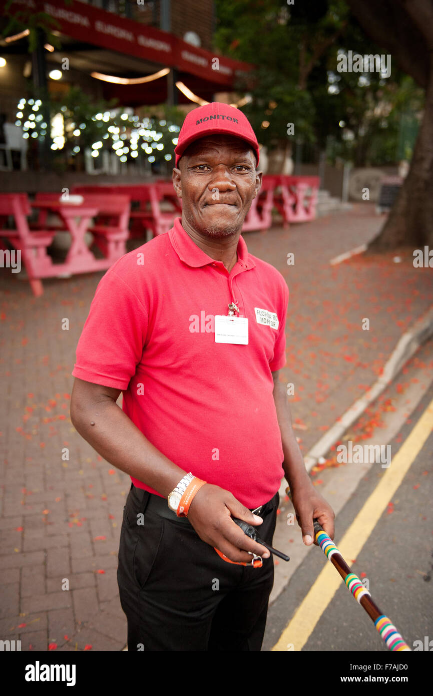 A car guard with a traditional Zulu war club, at the sidewalk cafe ...