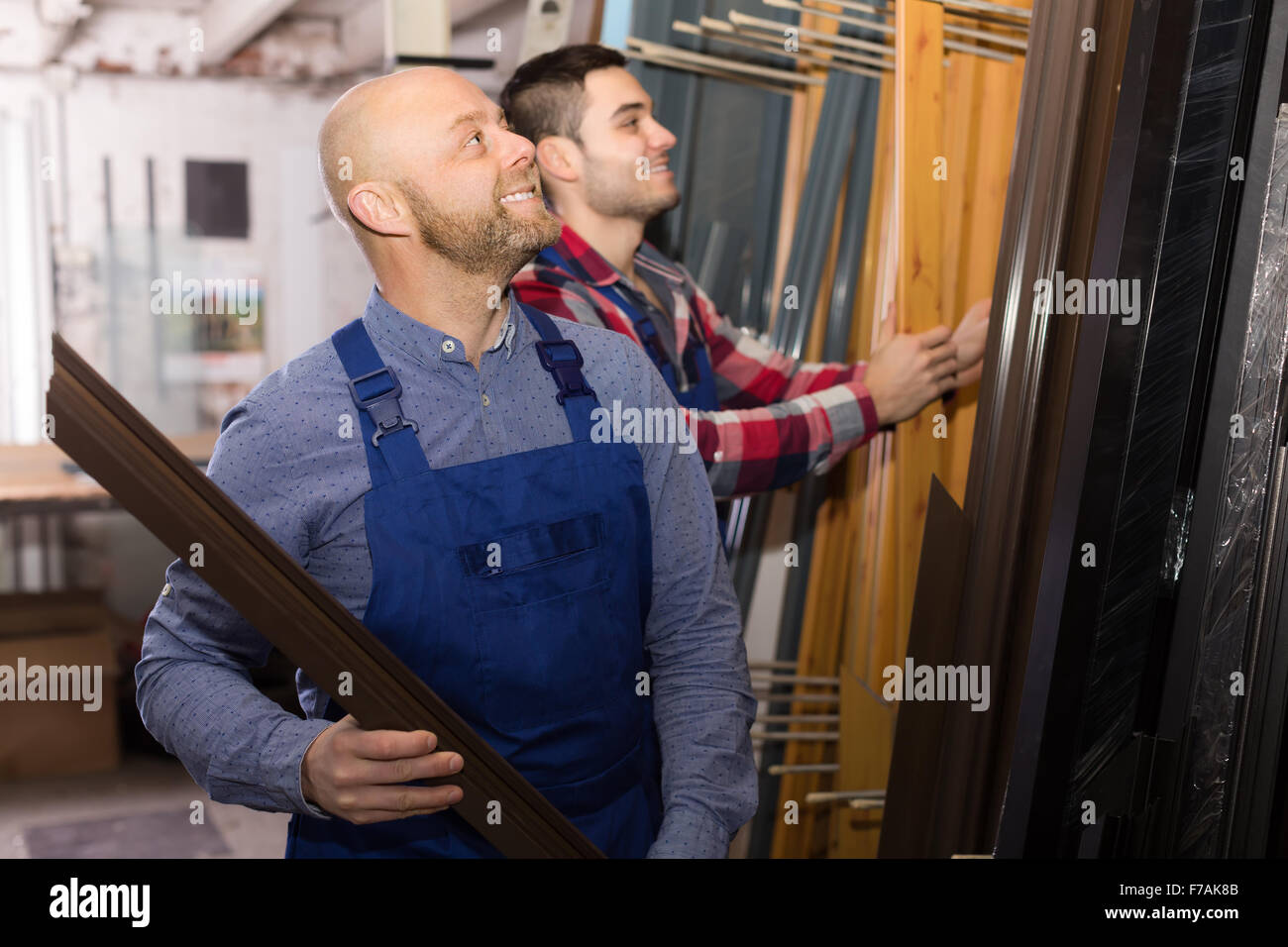 Two happy workers in uniform choosing PVC window profile at stand Stock ...