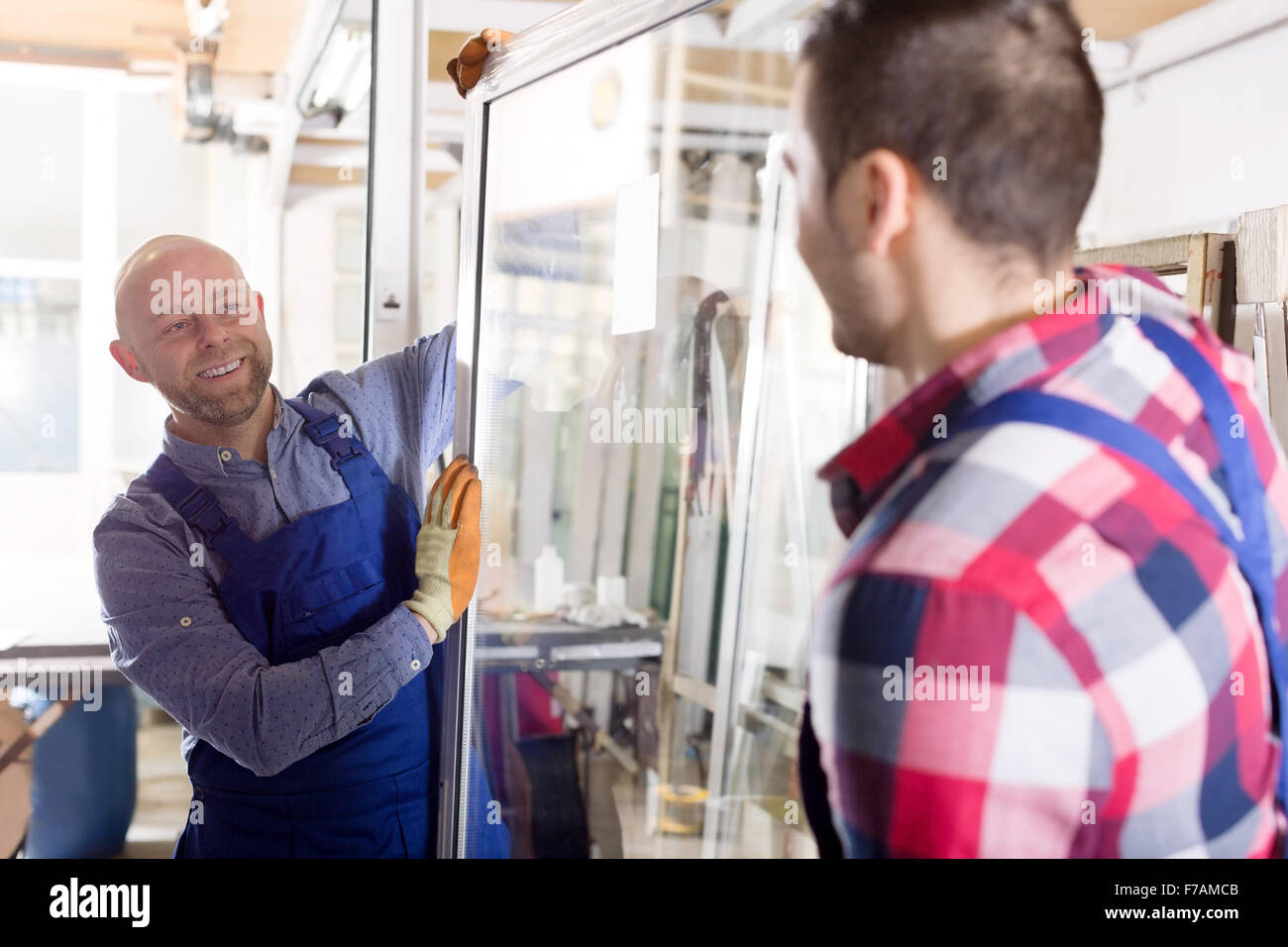 Two happy workmen with windows production at modern factory Stock Photo ...
