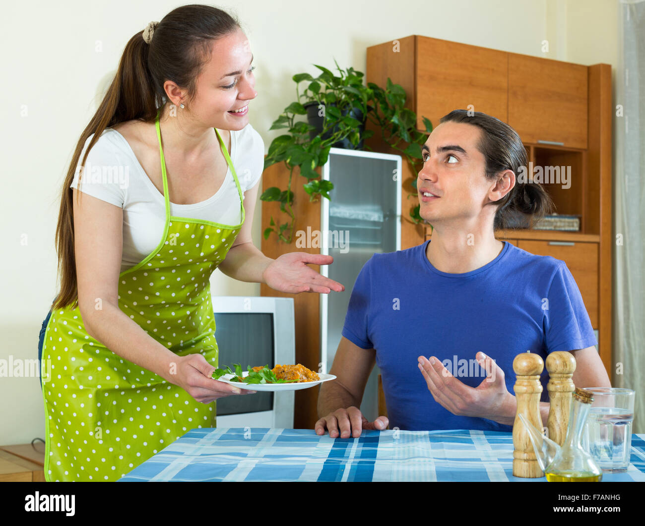 Smiling young woman serving food her beloved man at table Stock Photo ...