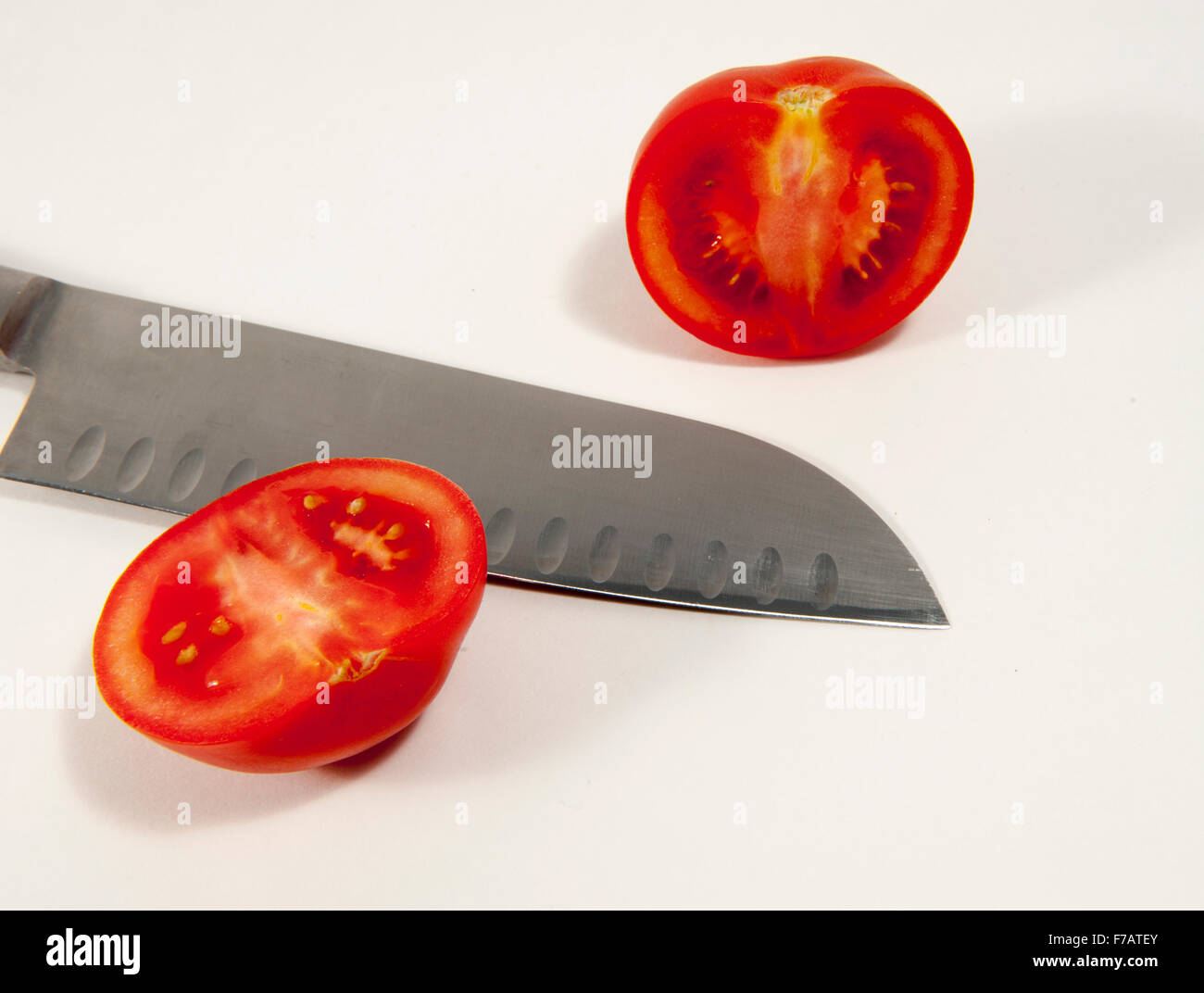 Tomato cut in half and a knife Stock Photo - Alamy
