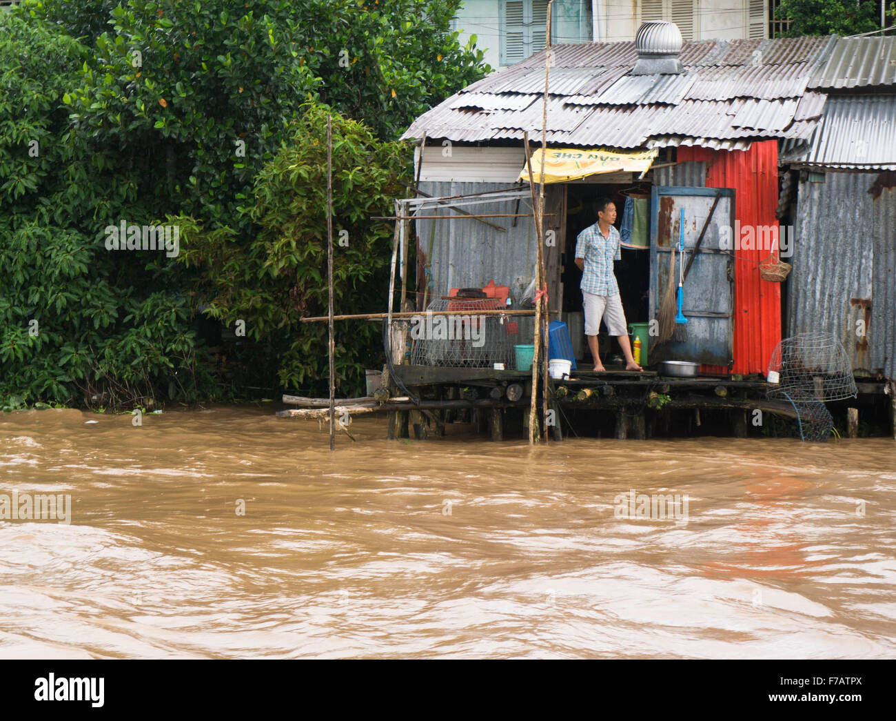 Sa Dec, Mekong Delta, Vietnam: Man watches river traffic from his house ...