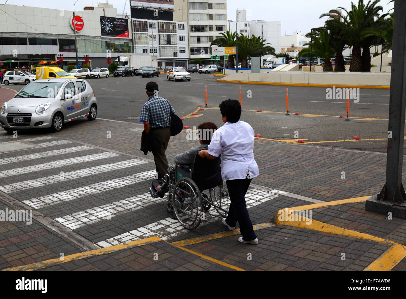 Woman in wheelchair using access ramp in pavement at pedestrian ...