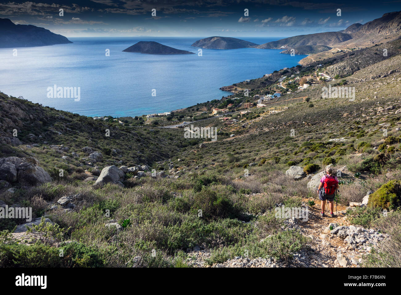 Small figure with red rucksack above Skalia Kalymnos Stock Photo - Alamy