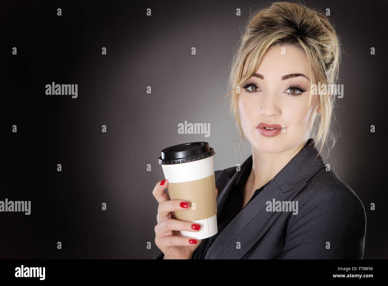 business woman drinking from a take away paper cup shot in the studio ...