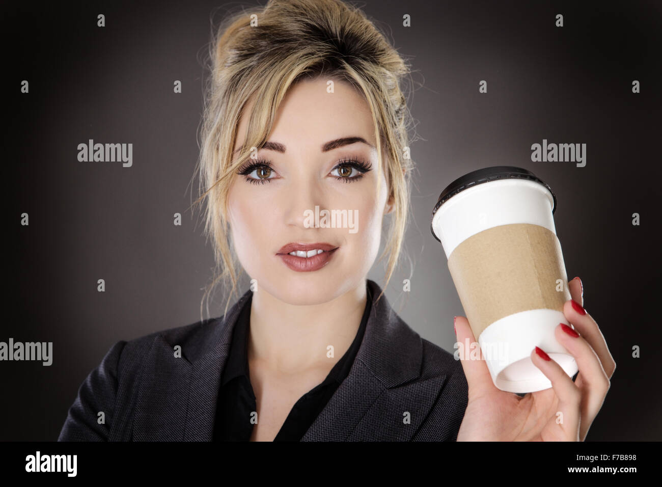 business woman drinking from a take away paper cup shot in the studio ...