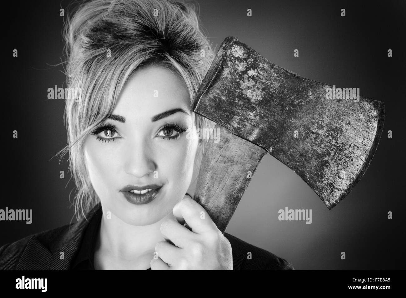 business woman holding a large axe shot in the studio on a gray ...