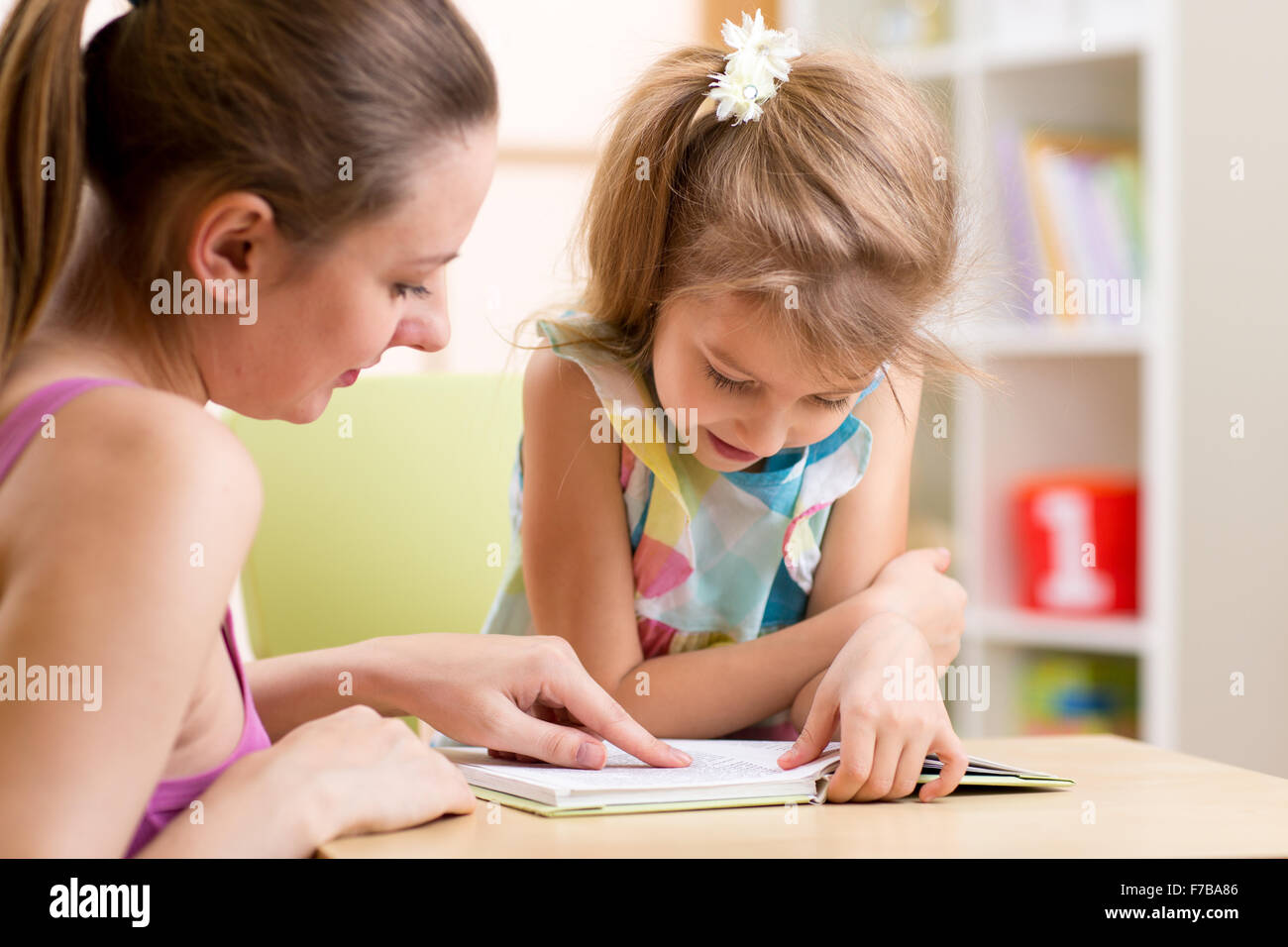 Mother teaching child daughter to read Stock Photo - Alamy