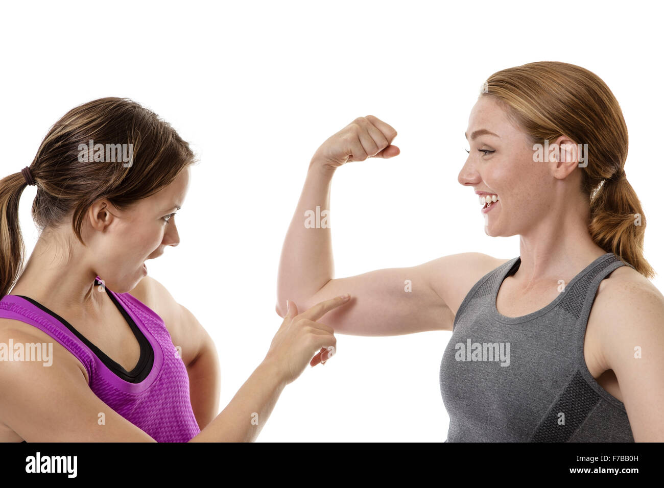 two fitness woman one showing the other how strong she is by flexing ...