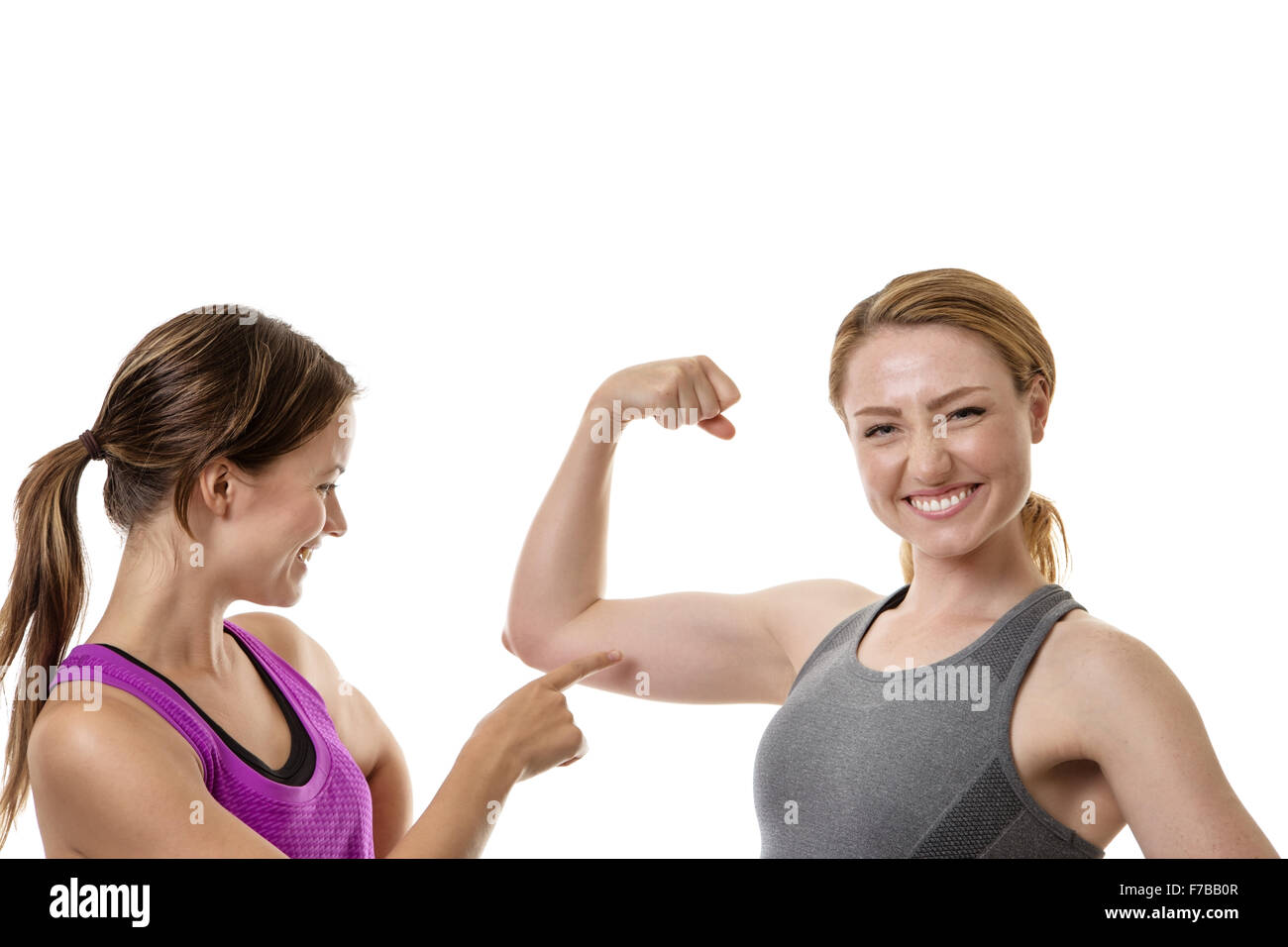 two fitness woman one showing the other how strong she is by flexing ...