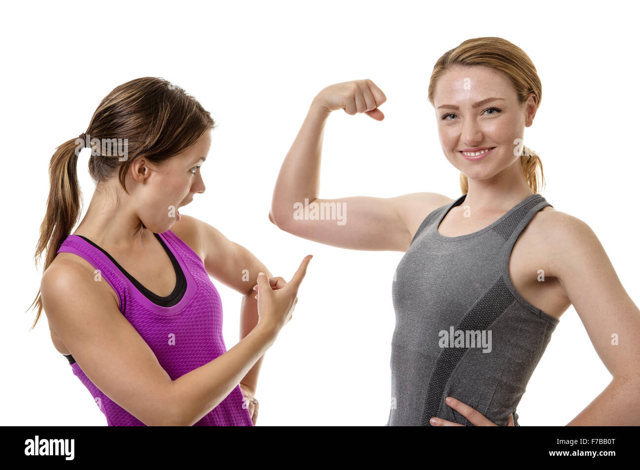 two fitness woman one showing the other how strong she is by flexing ...