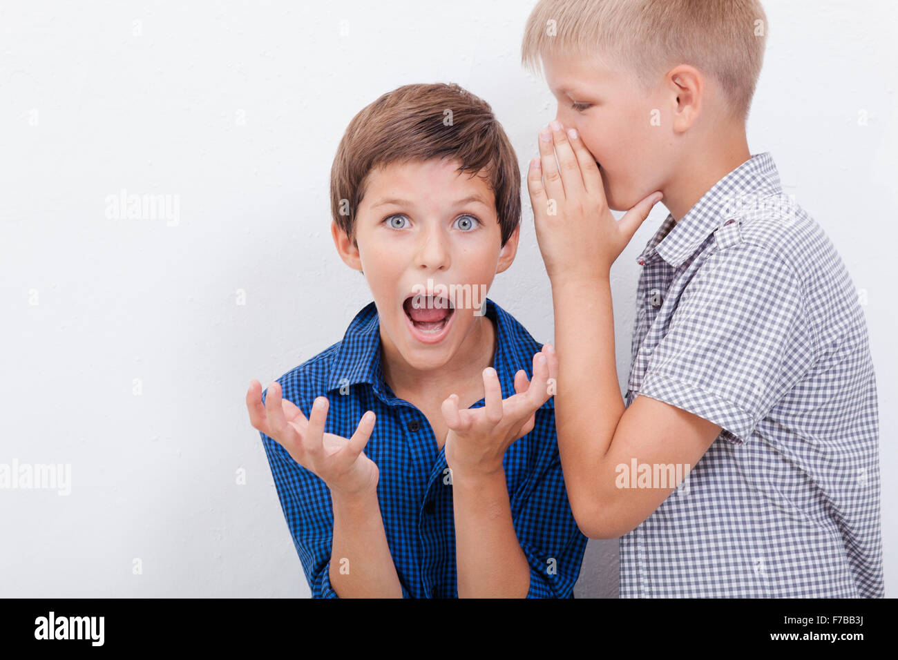 Teenage boy whispering in the ear a secret to friendl on white ...