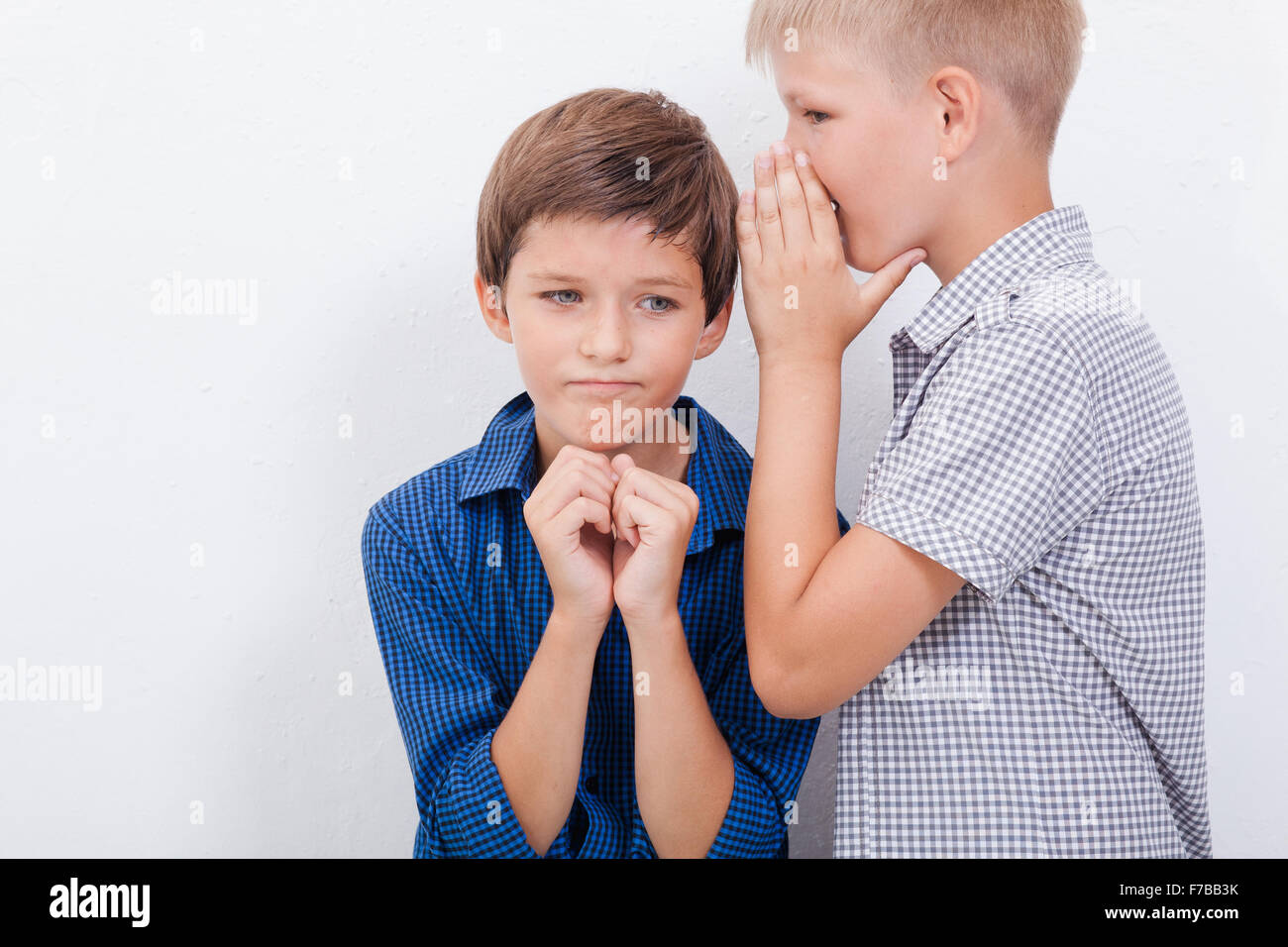 Teenage boy whispering in the ear a secret to friendl on white ...