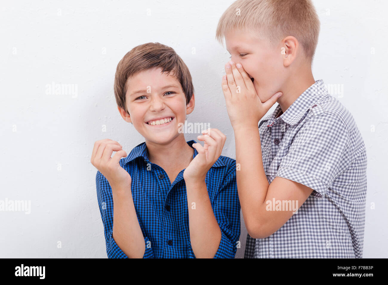 Teenage boy whispering in the ear a secret to friendl on white ...