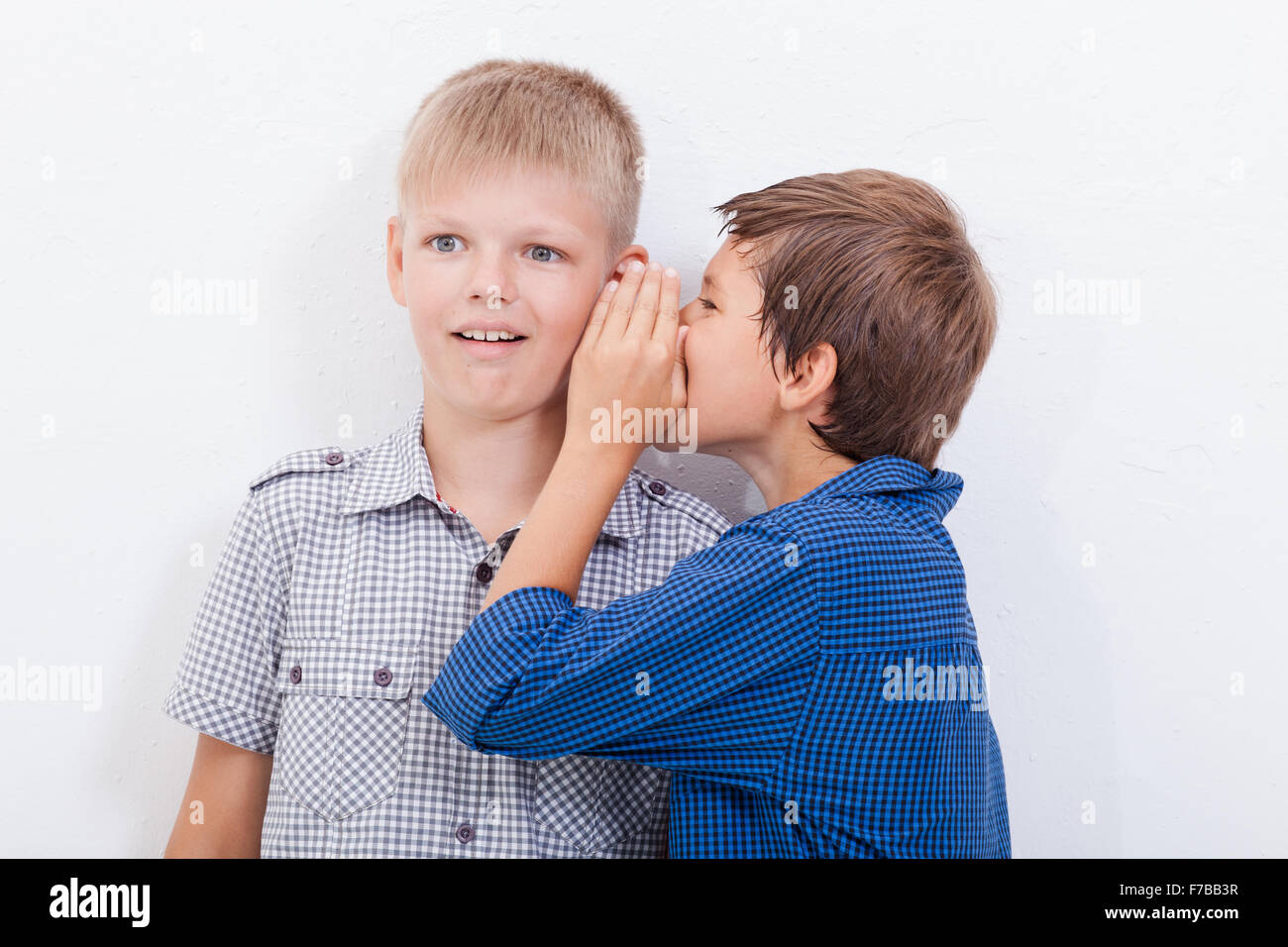Teenage boy whispering in the ear a secret to friendl on white ...