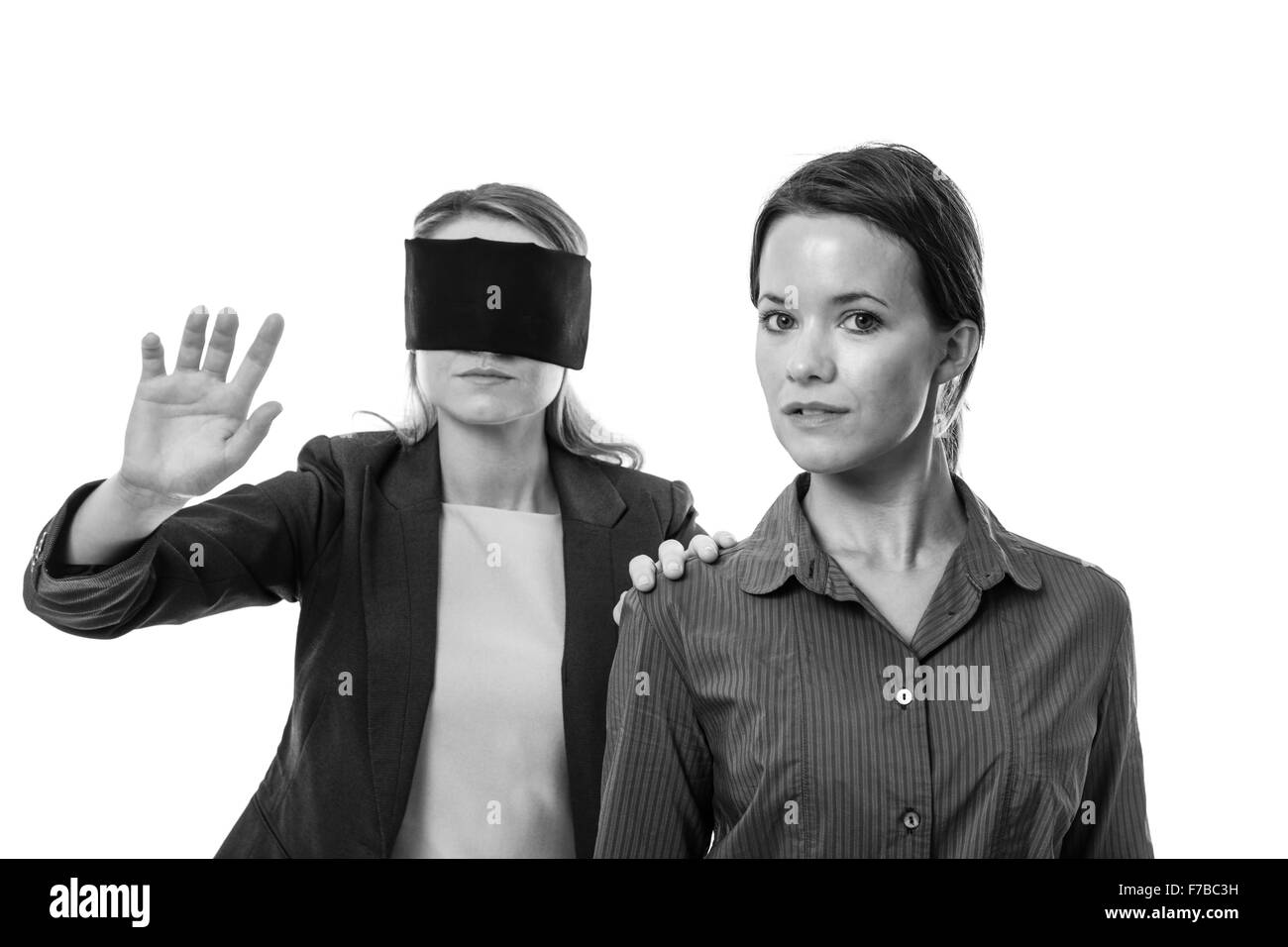 two business woman one blindfolded and the other helping Stock Photo ...