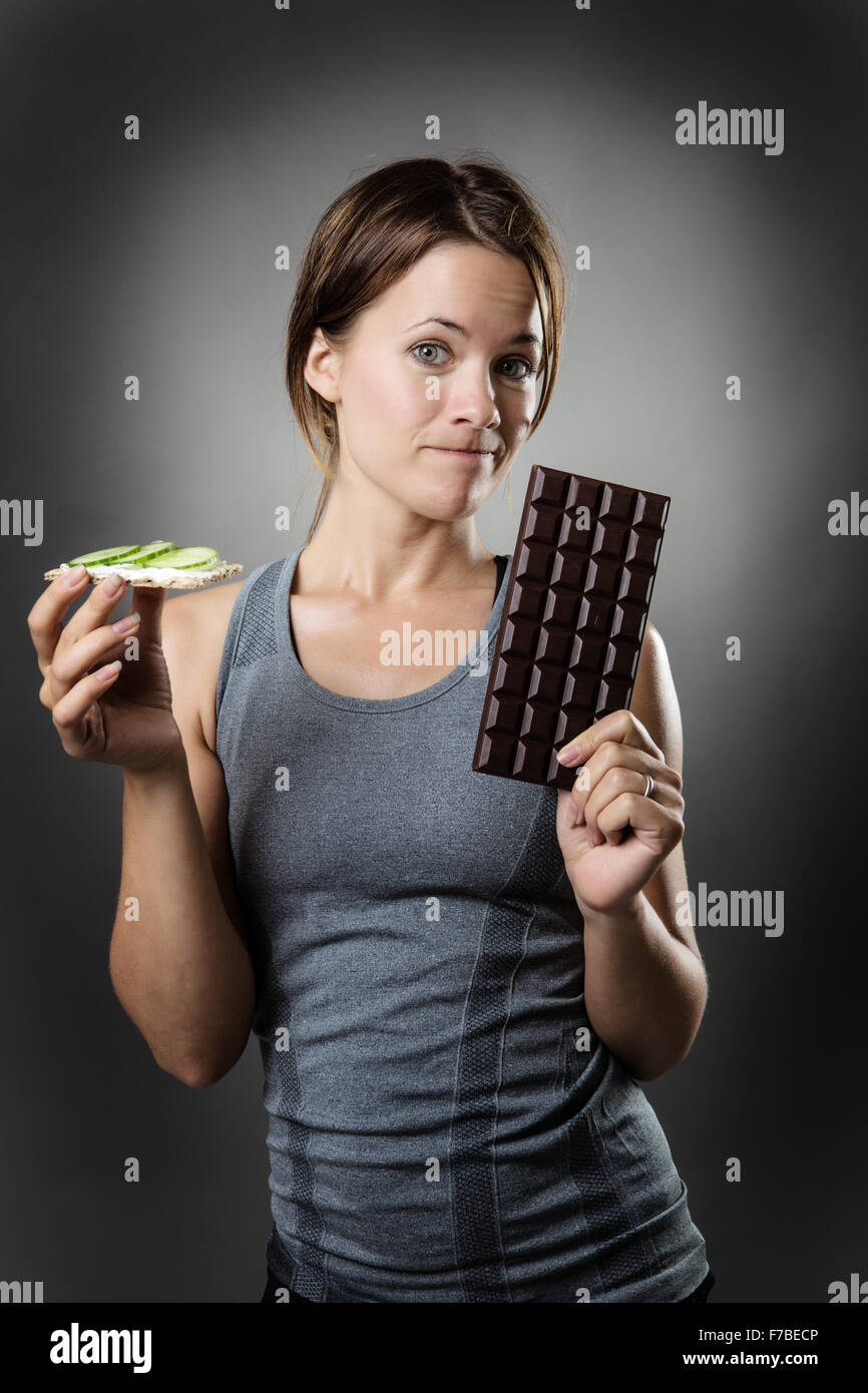 woman holding a crispbread in one hand and a large chocolate bar in the ...