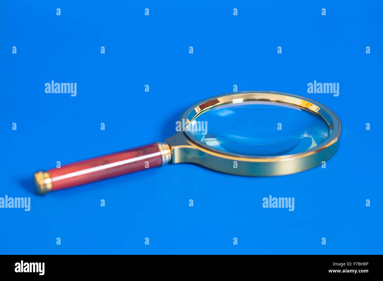Magnifying glass on blue background Stock Photo - Alamy
