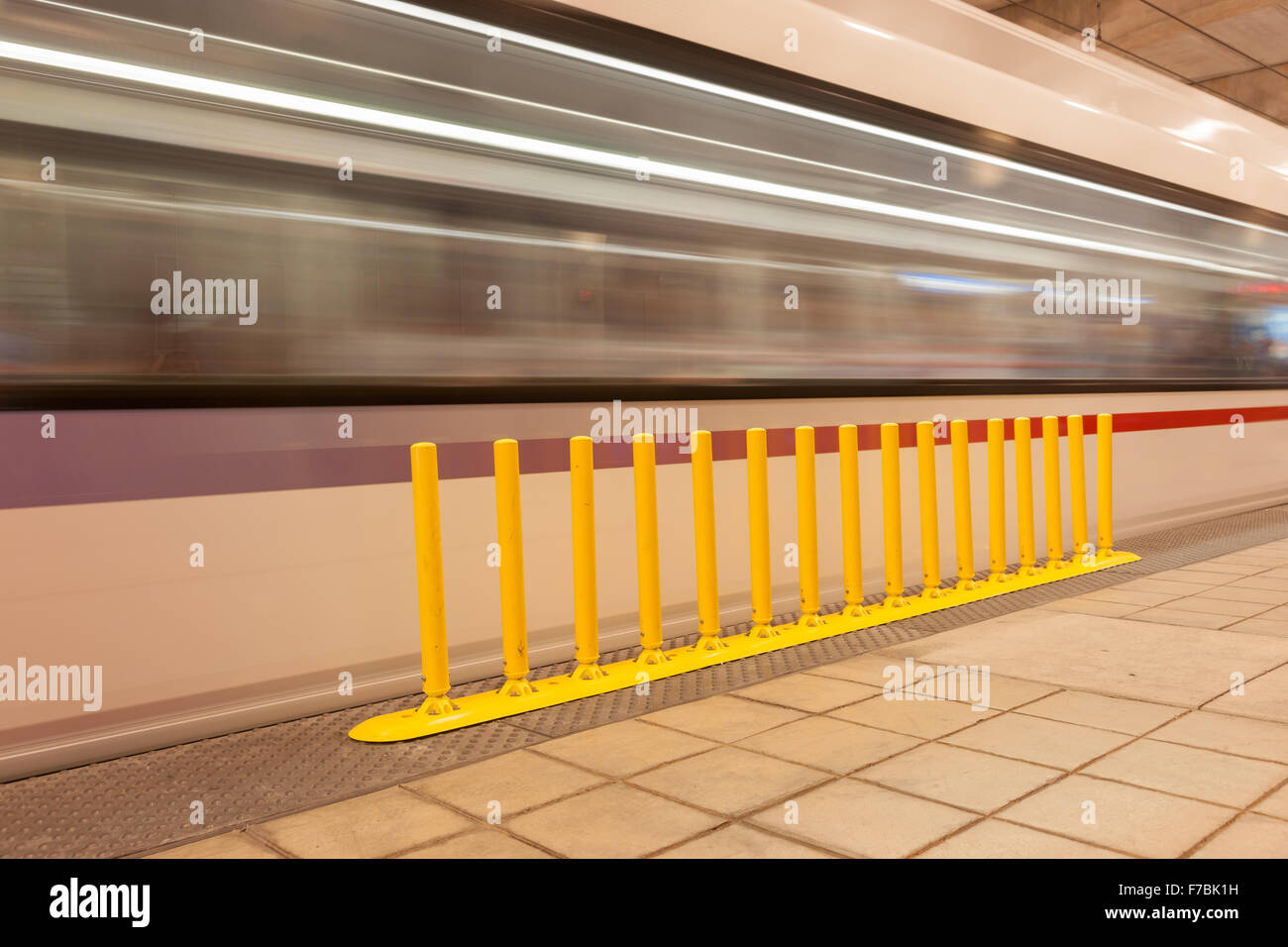 Yellow safety barrier on platform of subway as blurred image of train ...