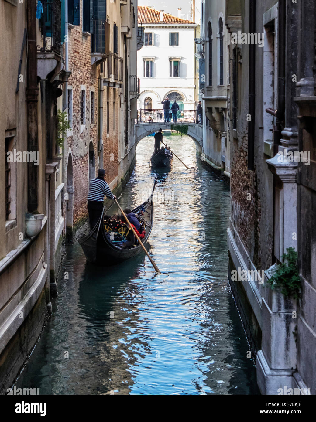 Venice, Italy. Two Gondoliers steer gondolas along a narrow Venetian ...