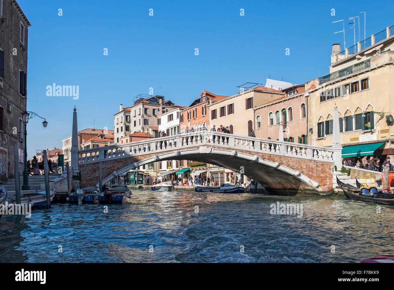 Venice, Stone bridge over canal lined with Venetian houses and shops ...