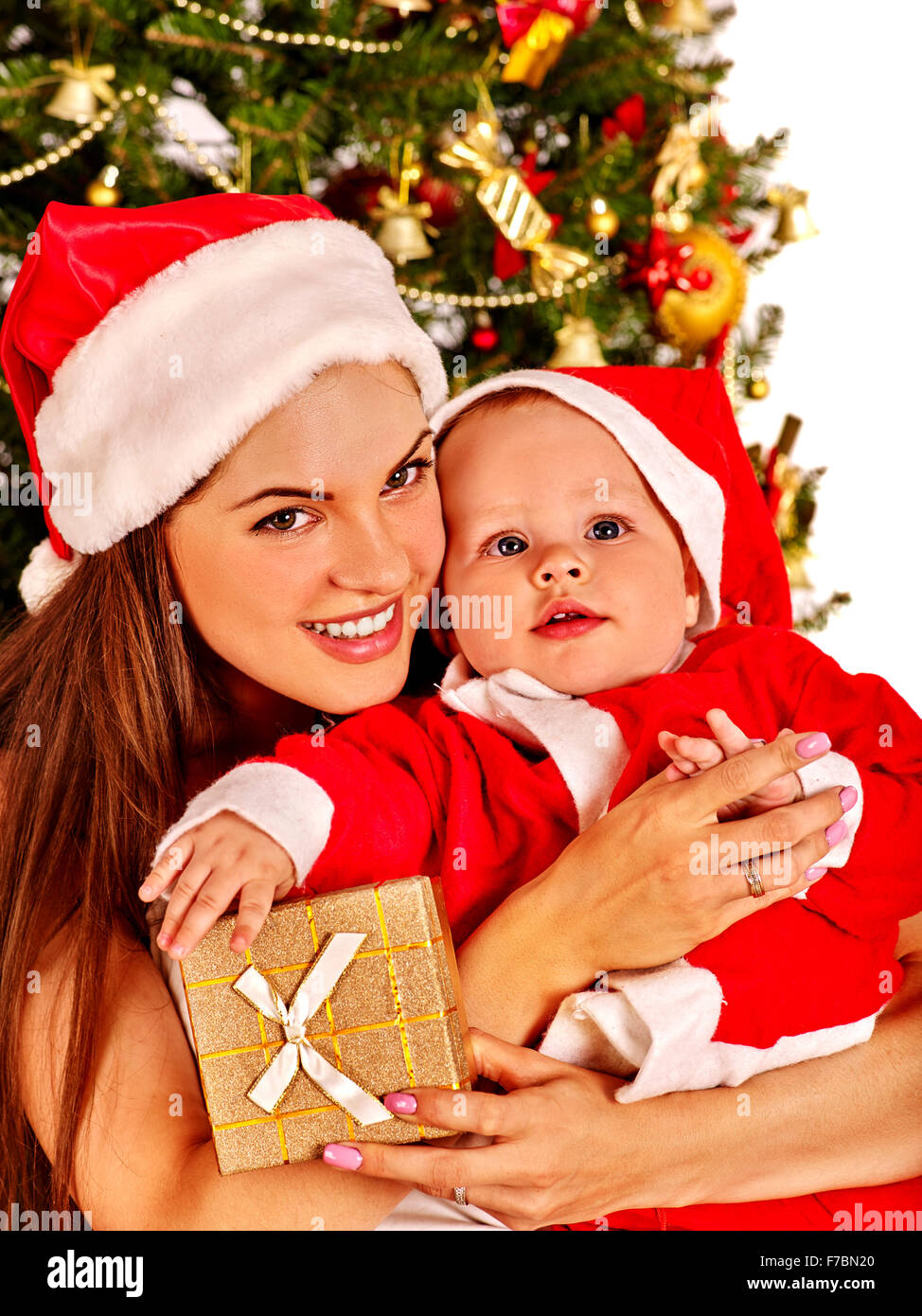 Mom wearing Santa hat holding baby under Christmas tree Stock Photo - Alamy