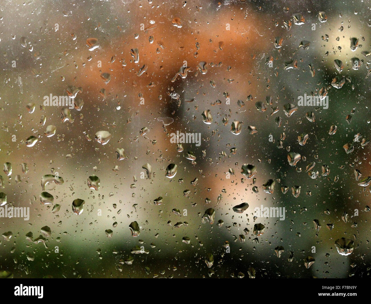 Raindrops on a window pane with muted Autumn colours in the background ...