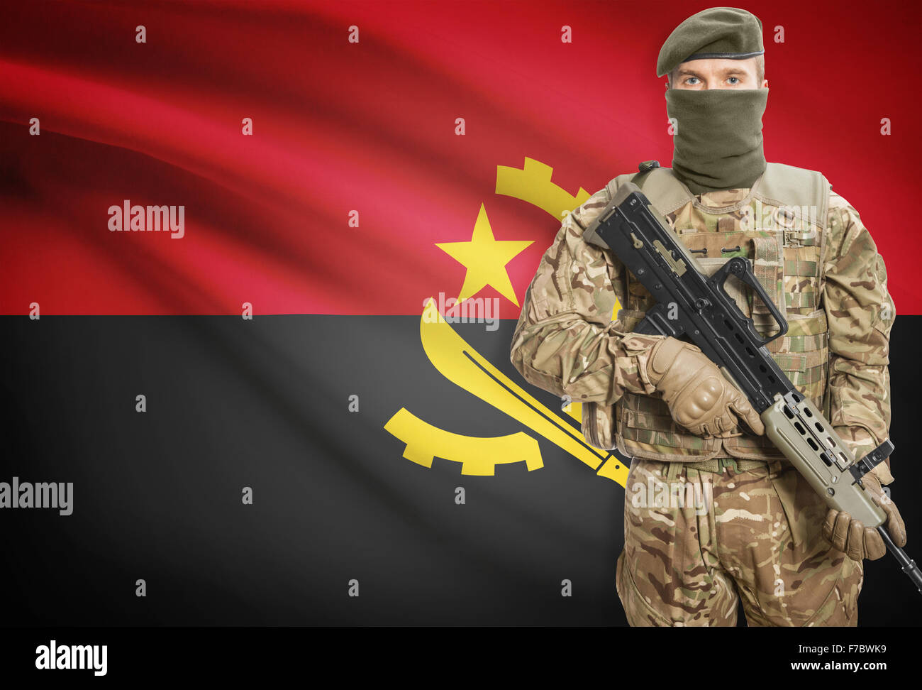 Soldier holding machine gun with national flag on background - Angola ...