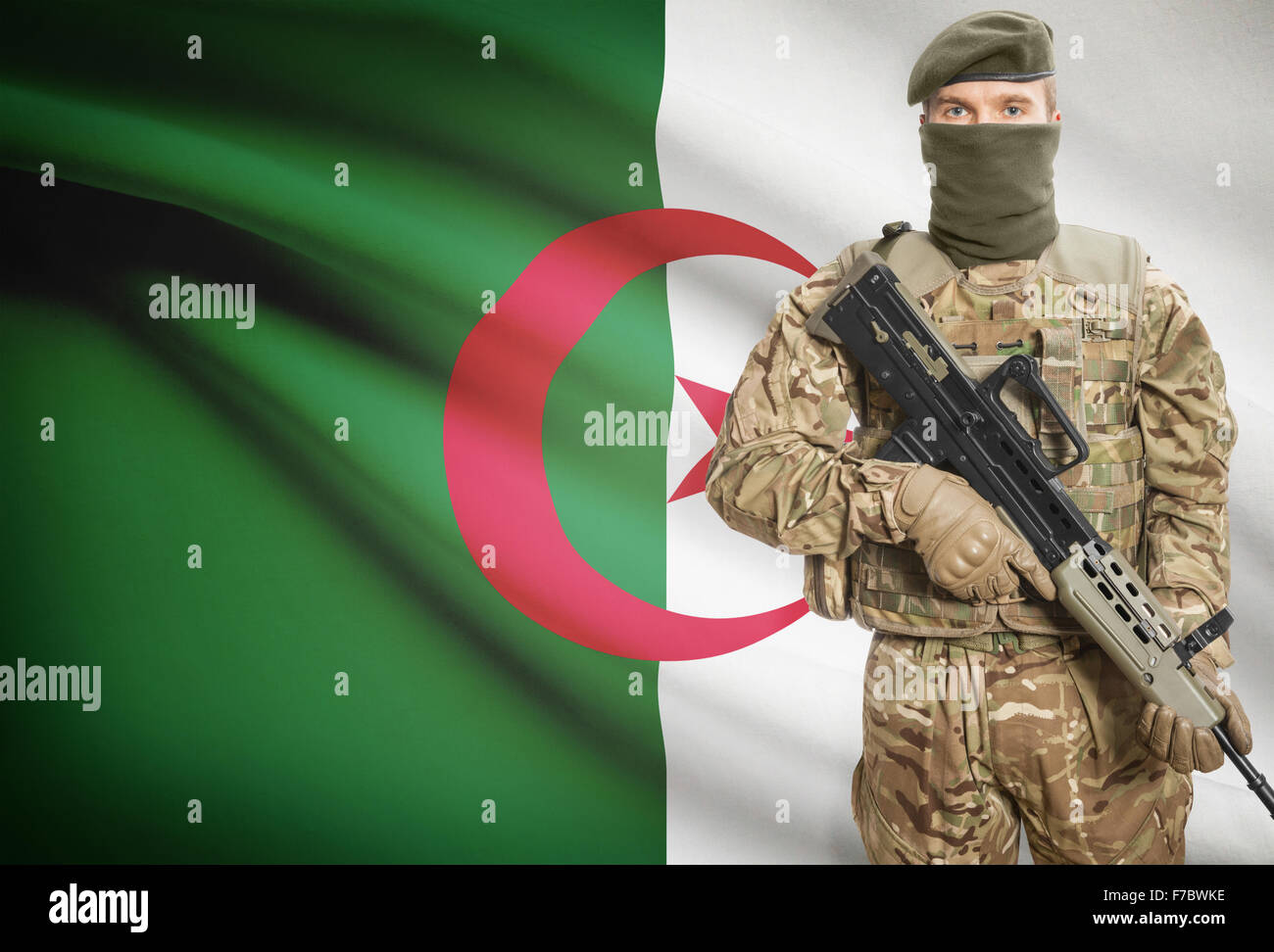 Soldier holding machine gun with national flag on background - Algeria ...