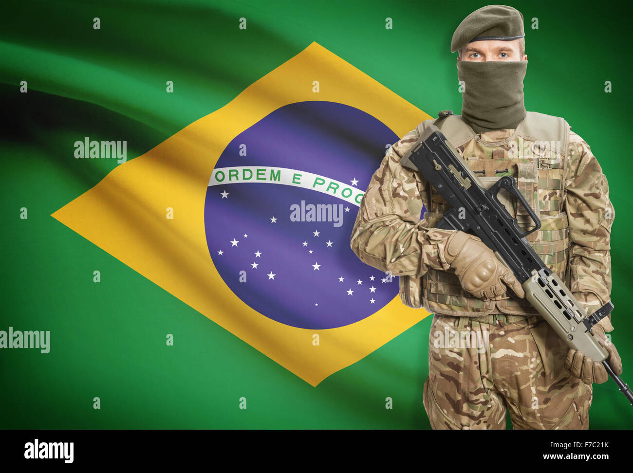 Soldier holding machine gun with national flag on background - Brazil ...