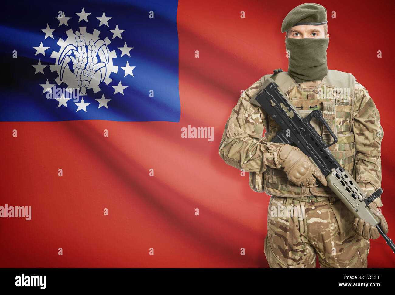 Soldier holding machine gun with national flag on background - Burma ...