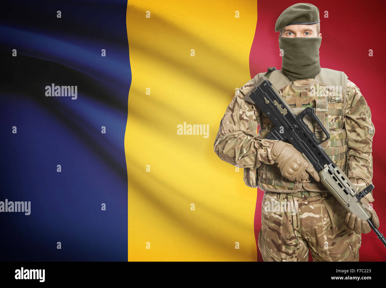 Soldier holding machine gun with national flag on background - Chad ...