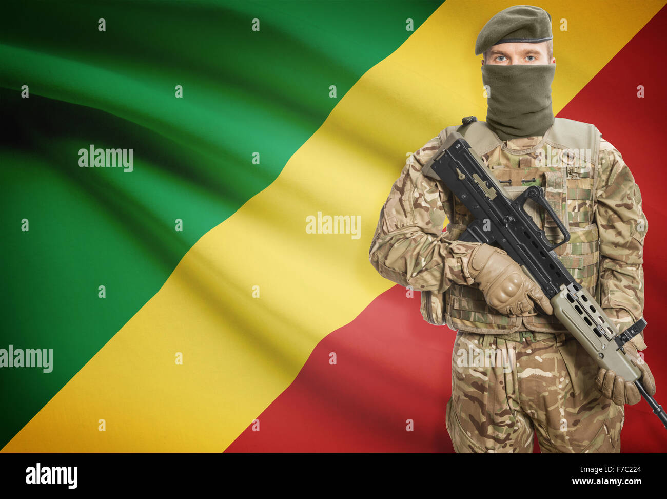Soldier holding machine gun with national flag on background - Congo ...