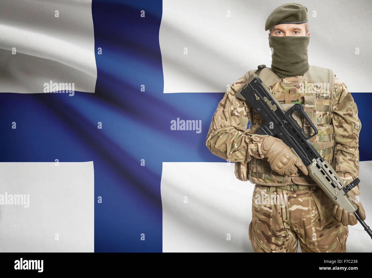 Soldier holding machine gun with national flag on background - Finland ...