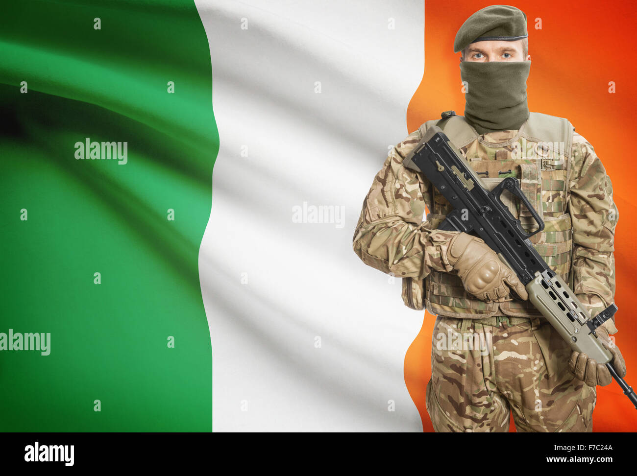 Soldier holding machine gun with national flag on background - Ireland ...