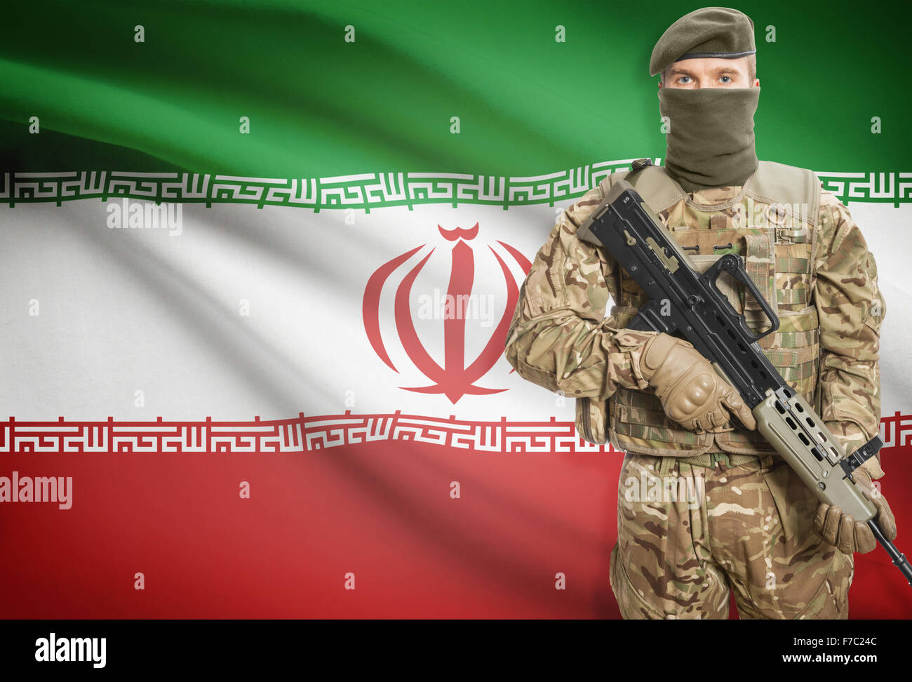 Soldier holding machine gun with national flag on background - Iran ...