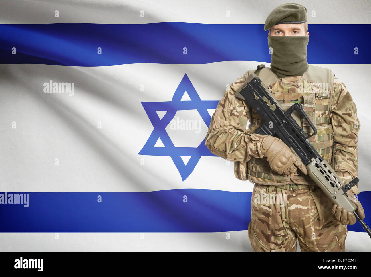 Soldier holding machine gun with national flag on background - Israel ...