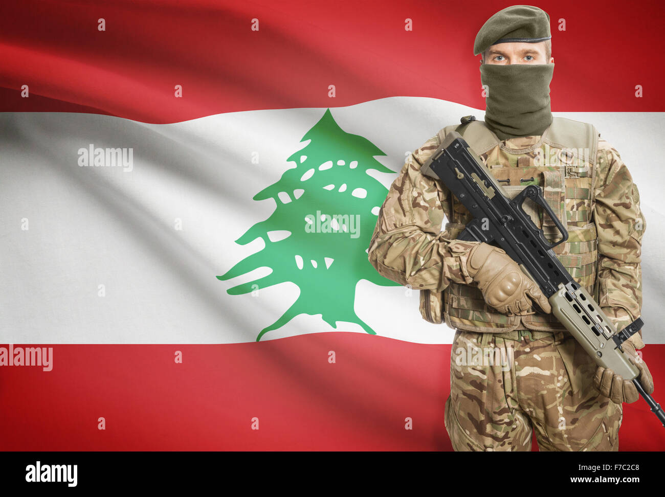 Soldier holding machine gun with national flag on background - Lebanon ...