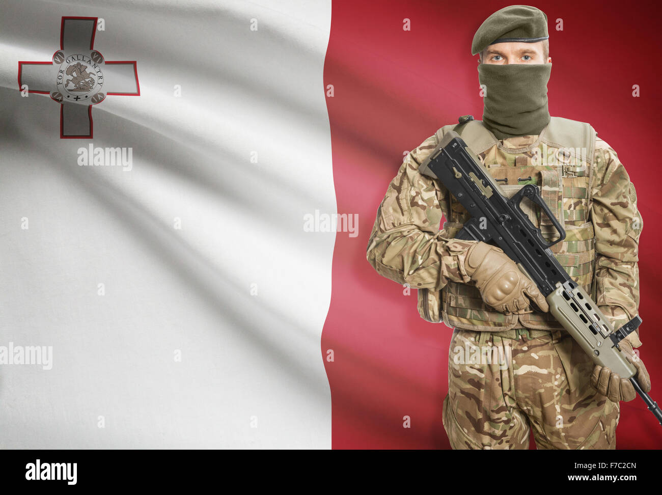 Soldier holding machine gun with national flag on background - Malta ...