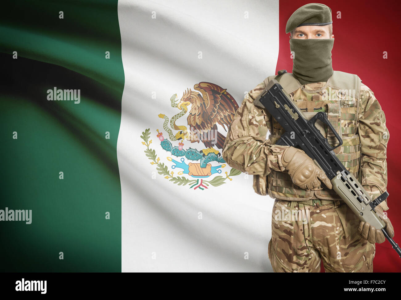 Soldier holding machine gun with national flag on background - Mexico ...