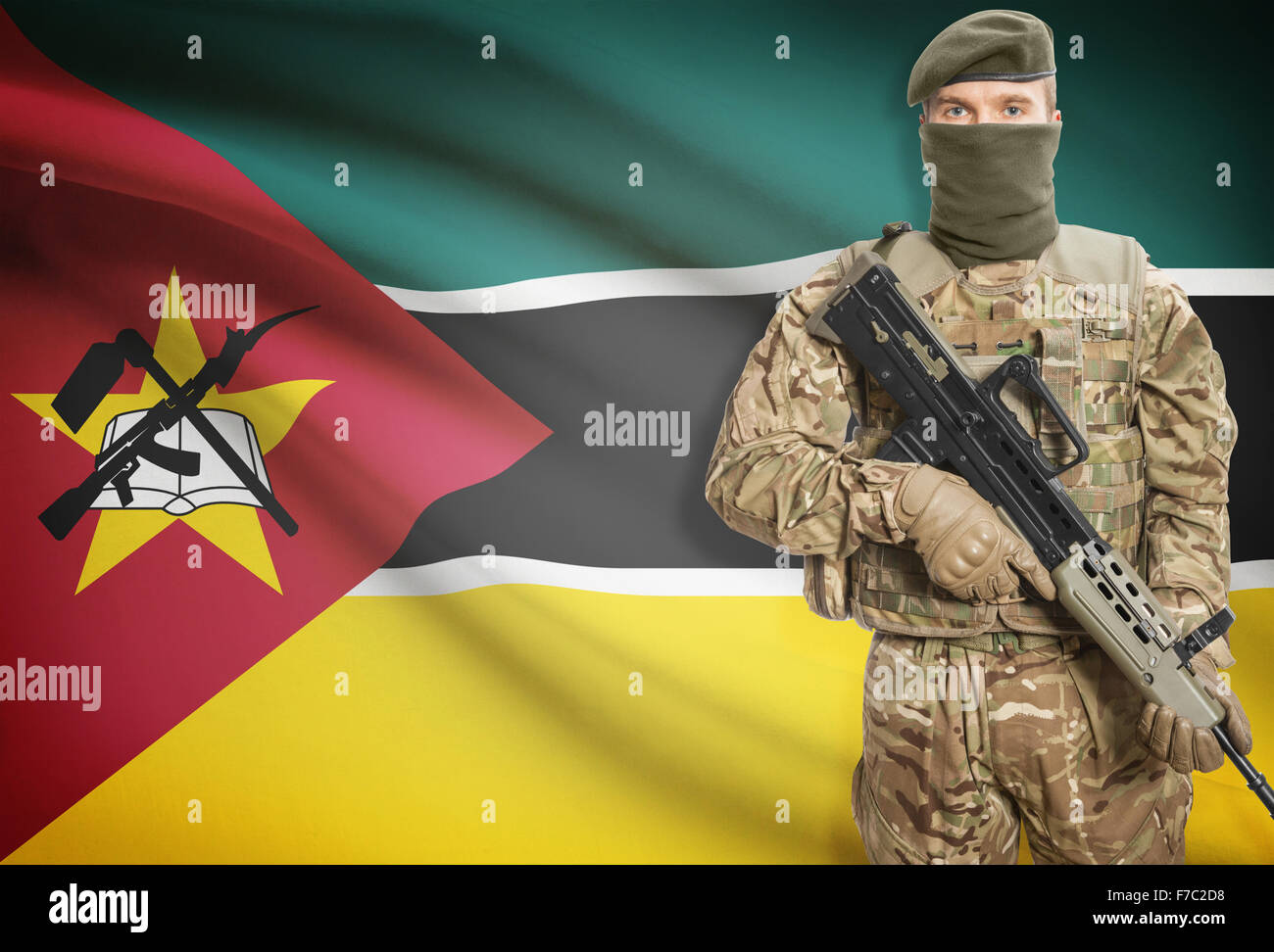 Soldier holding machine gun with national flag on background ...
