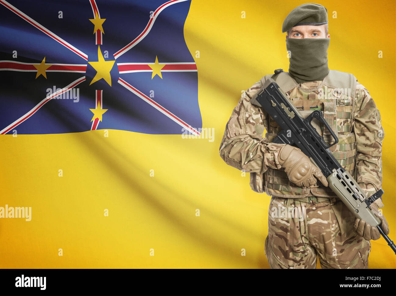 Soldier holding machine gun with national flag on background - Niue ...