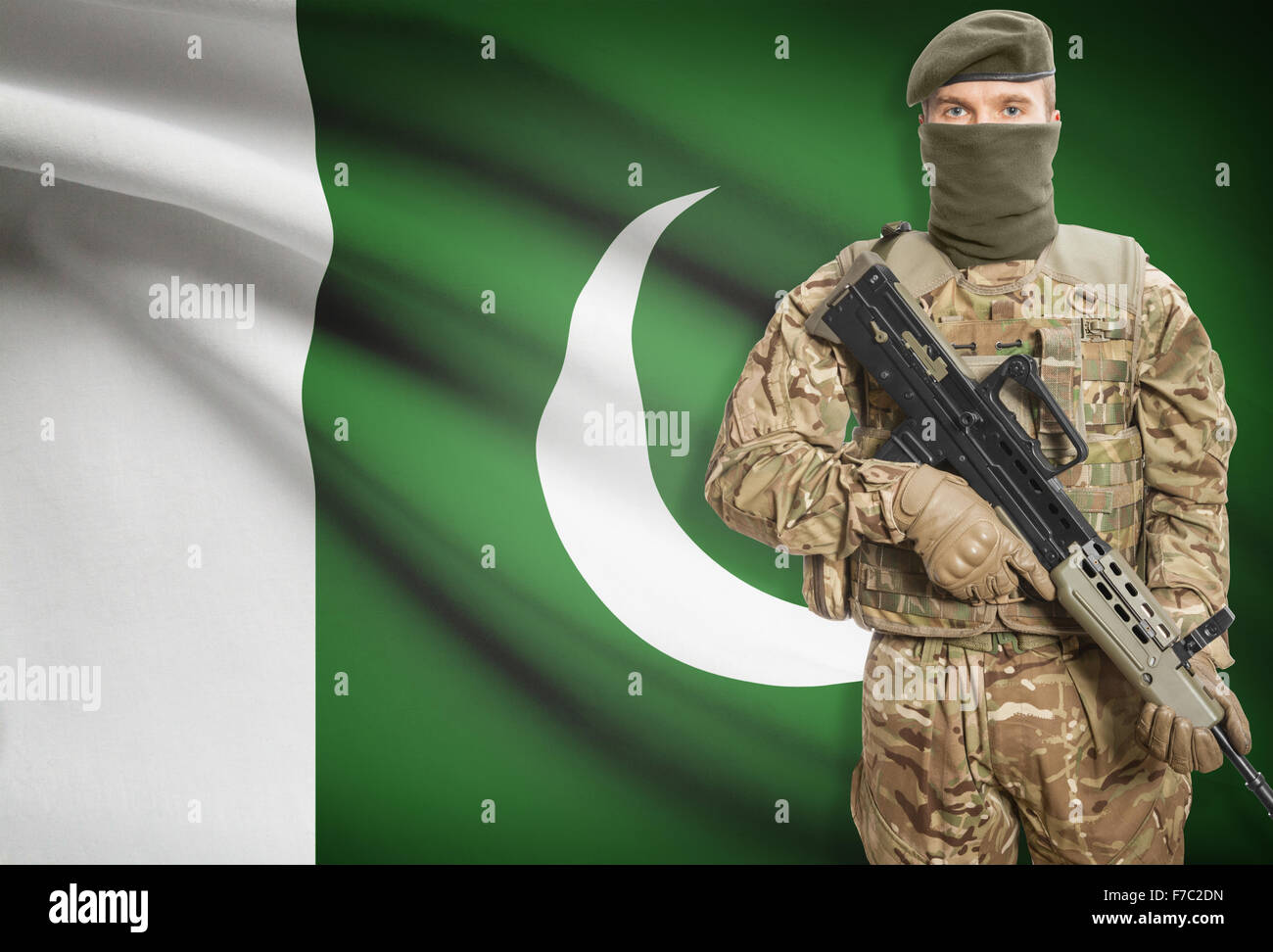 Soldier holding machine gun with national flag on background - Pakistan ...